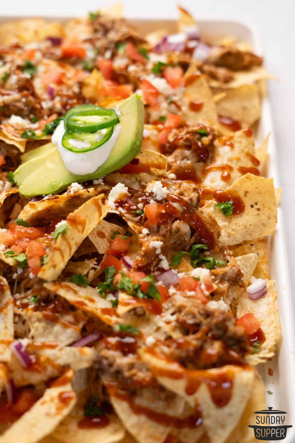 Oven-Baked Pulled Pork Nachos with Creamy Sour Cream Drizzle
